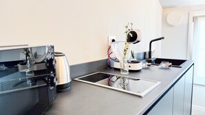Uma cozinha moderna com um fogão de indução embutido, uma máquina de café e um design de bancada elegante.