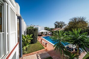 Quintal residencial com piscina, móveis de pátio e vista para casas vizinhas.