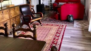 Um quarto com uma mesa de jantar de madeira, um sofá vermelho, uma poltrona vermelha e um tapete estampado.