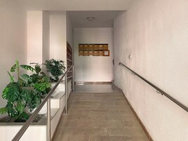 Uma escada com corrimão, plantas em vasos e um armário fixado na parede com gavetas.