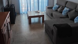 Uma sala de estar com sofá, mesa de centro e rack para televisão.
