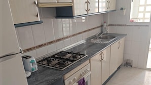 Cozinha com fogão a gás, forno e pia.