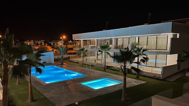 Um edifício moderno com piscina e palmeiras.