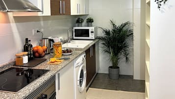 Uma cozinha moderna com micro-ondas, pia e um vaso de planta.