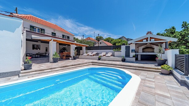 Piscina com terraço solar, área de estar ao ar livre e churrasqueira.