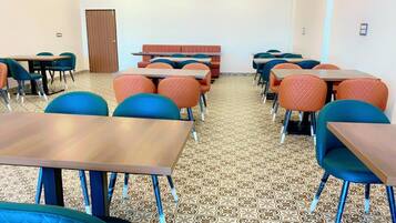 Uma sala de aula com mesas, cadeiras, carpete estampado e uma porta de madeira.
