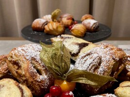 Diversos doces e sobremesas, incluindo um pastel com enfeite de folha e cerejas.
