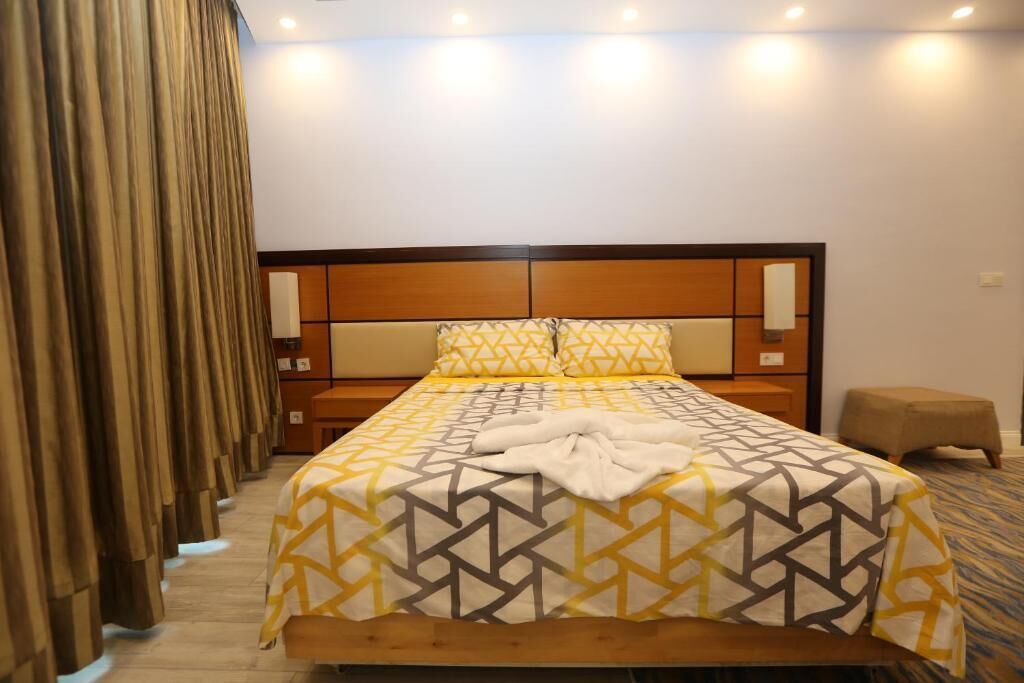 Quarto de hotel com cama grande, cabeceira de madeira e mesa de cabeceira.
