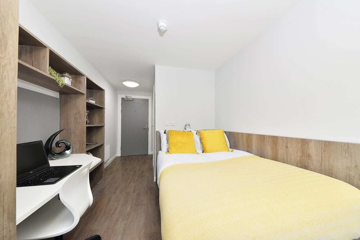 Quarto de hotel com uma cama, uma mesa e um computador.