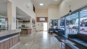 Um hall amplo com balcão de recepção, área de estar e grandes janelas com vista para a rua.