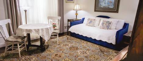 Quarto de hotel com cama, cadeira, mesa e abajur.