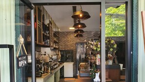 Um restaurante com decoração moderna, incluindo um bar, uma escadaria e vista para o verde lá fora.