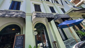 Um edifício com um café chamado “Marigold Lanna”, com área de estar ao ar livre e uma placa indicando café, waffles e brunch.