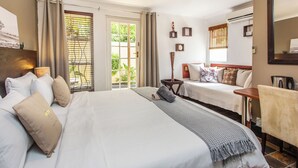 Quarto de hotel com uma cama grande, uma cama menor, uma escrivaninha e uma cadeira.