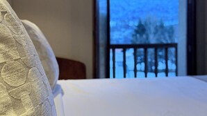Uma cama com vista para uma montanha através de uma porta de varanda aberta.