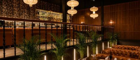 Uma área de bar com balcão de madeira, luminárias pendentes e assentos de couro.