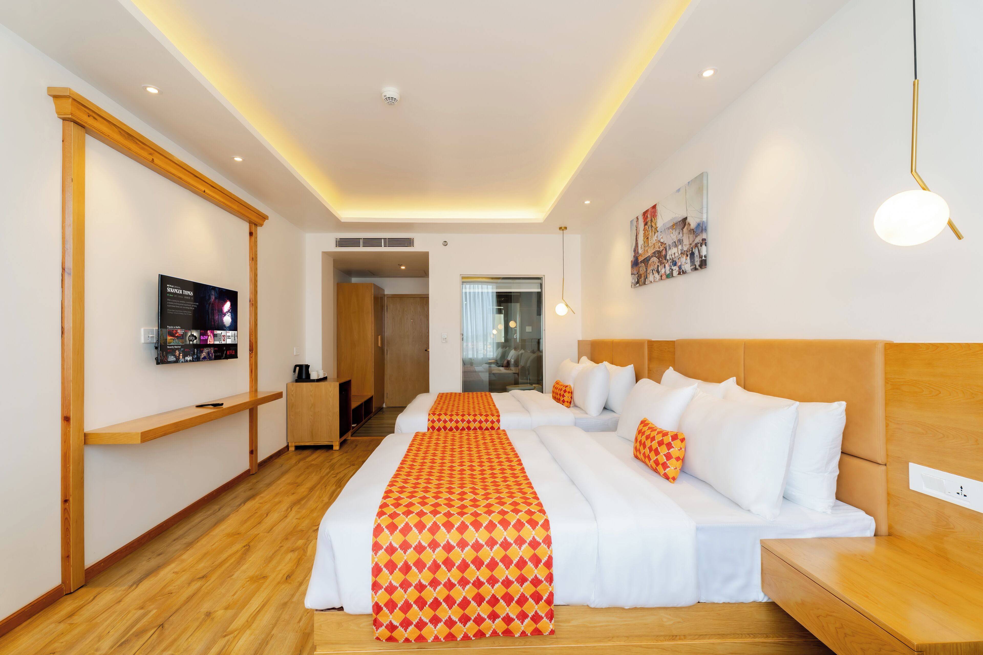 Quarto de hotel com uma cama grande, televisão, prateleira de madeira e design moderno no teto.