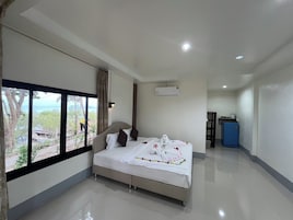 Quarto de hotel com cama, janela com vista, cozinha compacta e ar condicionado.