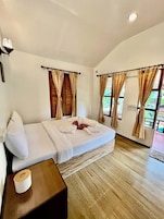Quarto de hotel com cama, cortinas, piso de madeira e mesa de cabeceira com caixa de lenços.