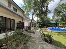 Um imóvel residencial com piscina, área de estar coberta ao ar livre e escadaria que leva à entrada.