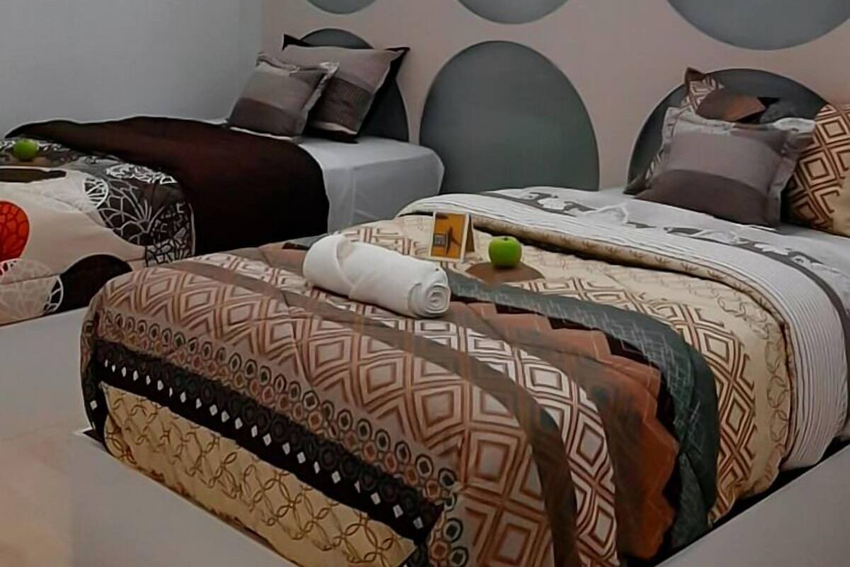 Quarto moderno com cama grande, roupa de cama estampada e decorações circulares na parede.