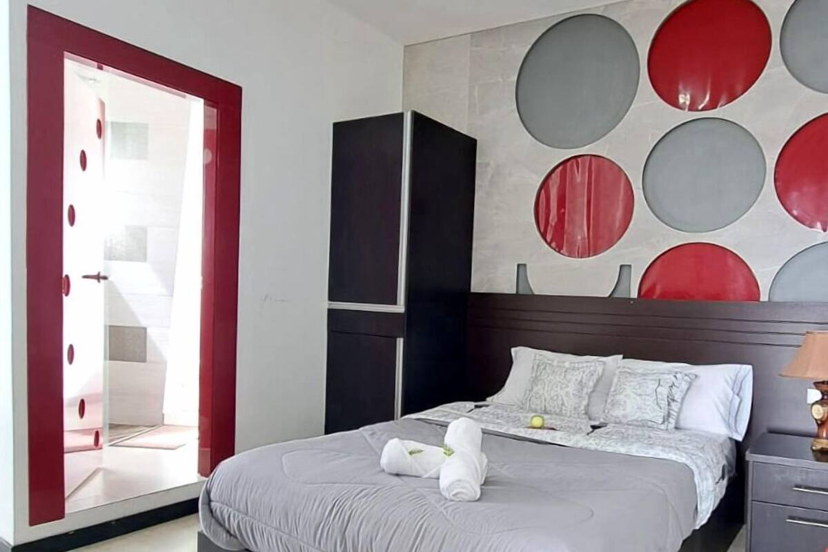 Quarto moderno com cama, guarda-roupa e parede com padrões circulares.
