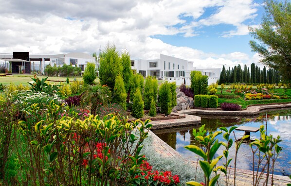 Um edifício moderno com jardim e lago.