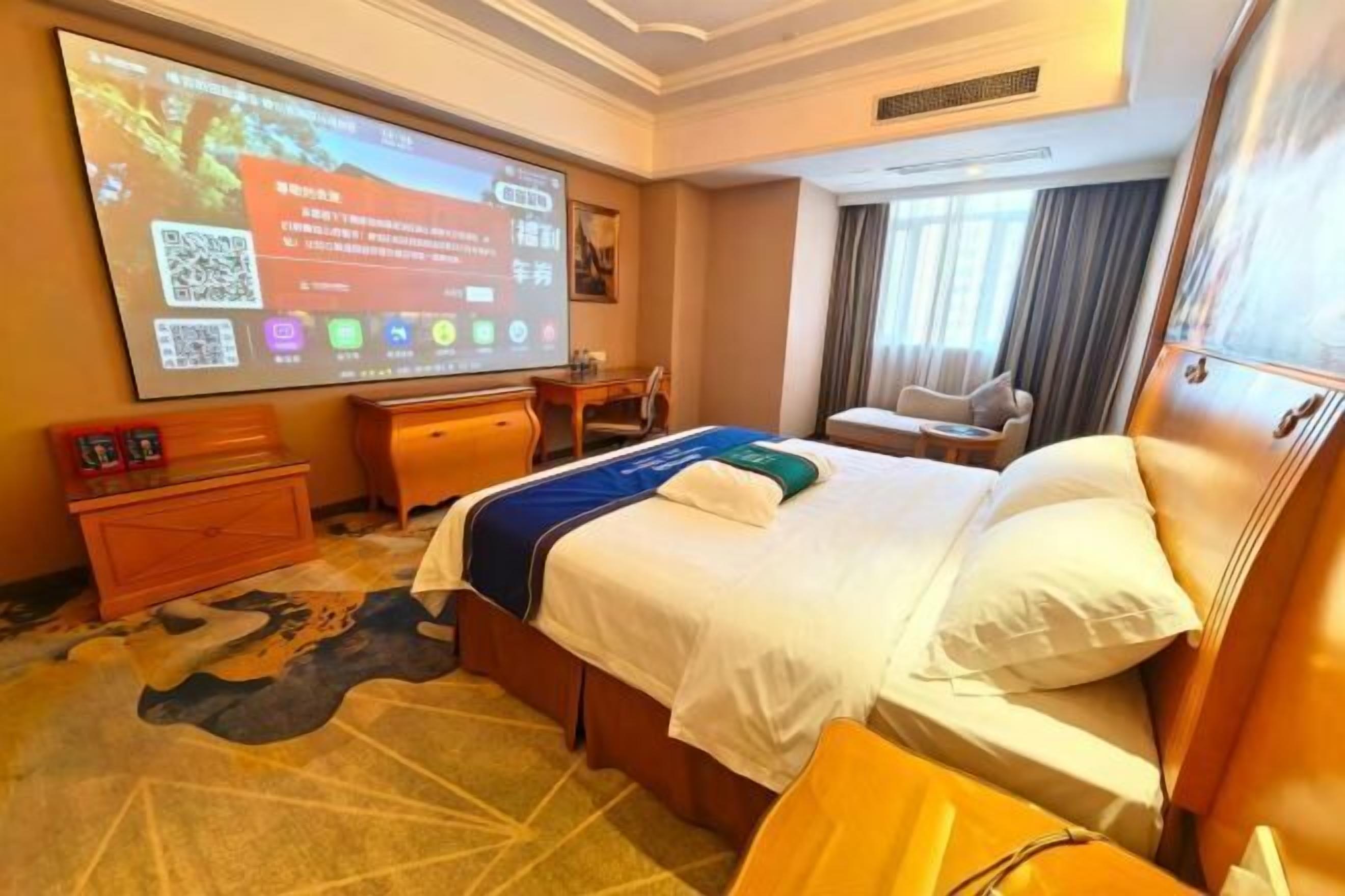 Quarto de hotel com cama, escrivaninha, cadeira, televisão e tapete.