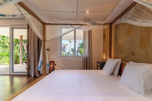 Um quarto espaçoso com uma cama grande, janela com vista para o verde e uma parede de pedra.