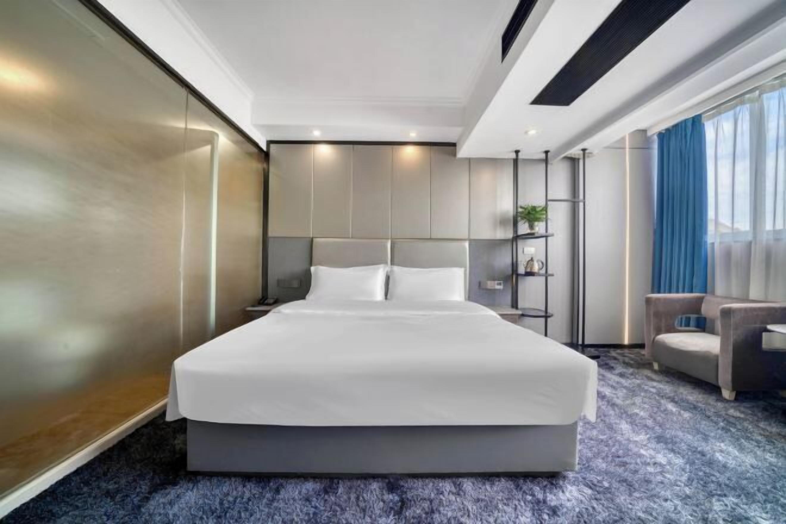 Quarto de hotel moderno com uma cama grande, um espaço de estar pequeno e vista para o exterior.