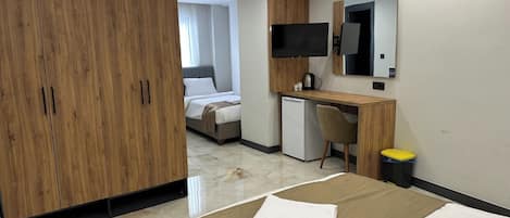 Quarto de hotel com cama, escrivaninha, televisão e guarda-roupa.
