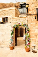 Edifício de pedra com porta de madeira e arco decorativo floral.