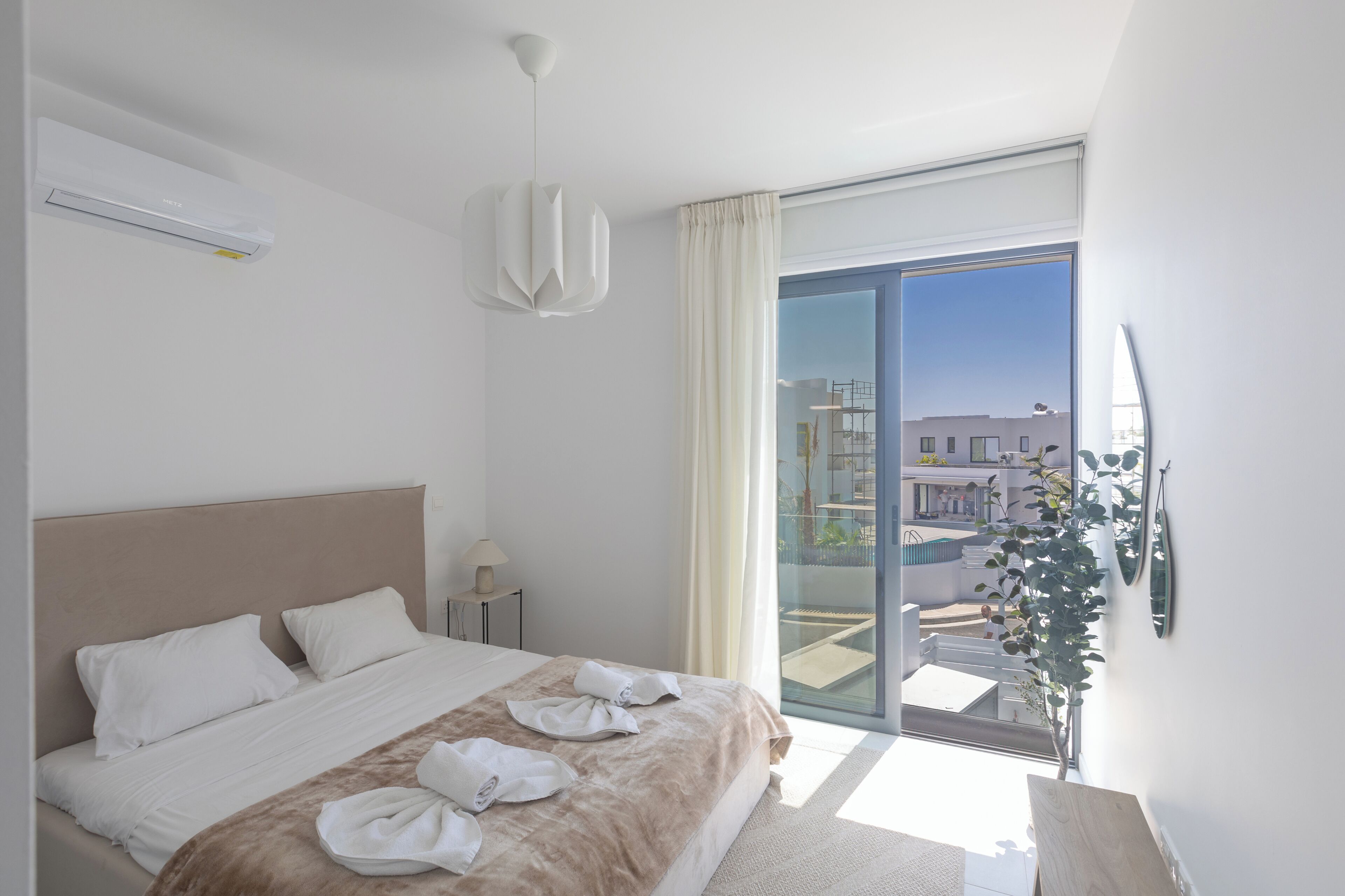 Quarto de hotel com cama, janela com cortinas, ventoinha no teto e vista para o exterior.