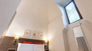 Quarto com cama, duas luminárias de cabeceira, mesa de cabeceira, janela e guarda-roupa.