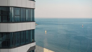 Um edifício moderno com grandes janelas que dão para um mar calmo e uma praia.