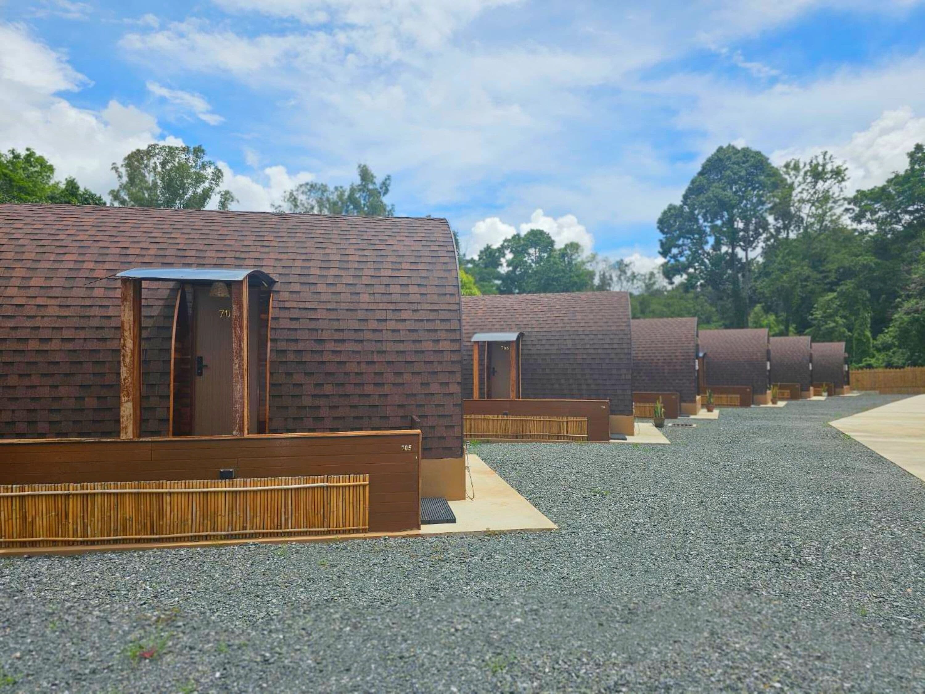 Uma fileira de cabanas pequenas e idênticas, cada uma com telhado inclinado, porta e um pequeno alpendre.