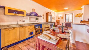 Uma cozinha com armários de madeira, bancada de granito e área de jantar com mesa posta para dois.