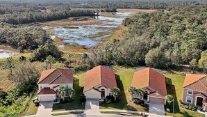 Zona residencial com casas de telhados vermelhos, cercada por vegetação exuberante e um rio.