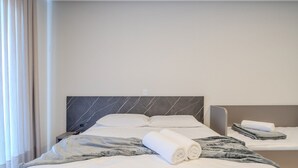 Quarto de hotel com cama, mesa de cabeceira e janela com cortinas.