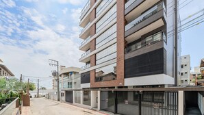 Edifício de vários andares com design arquitetônico moderno, combinando fachadas de tijolo e vidro, e uma entrada com portão.