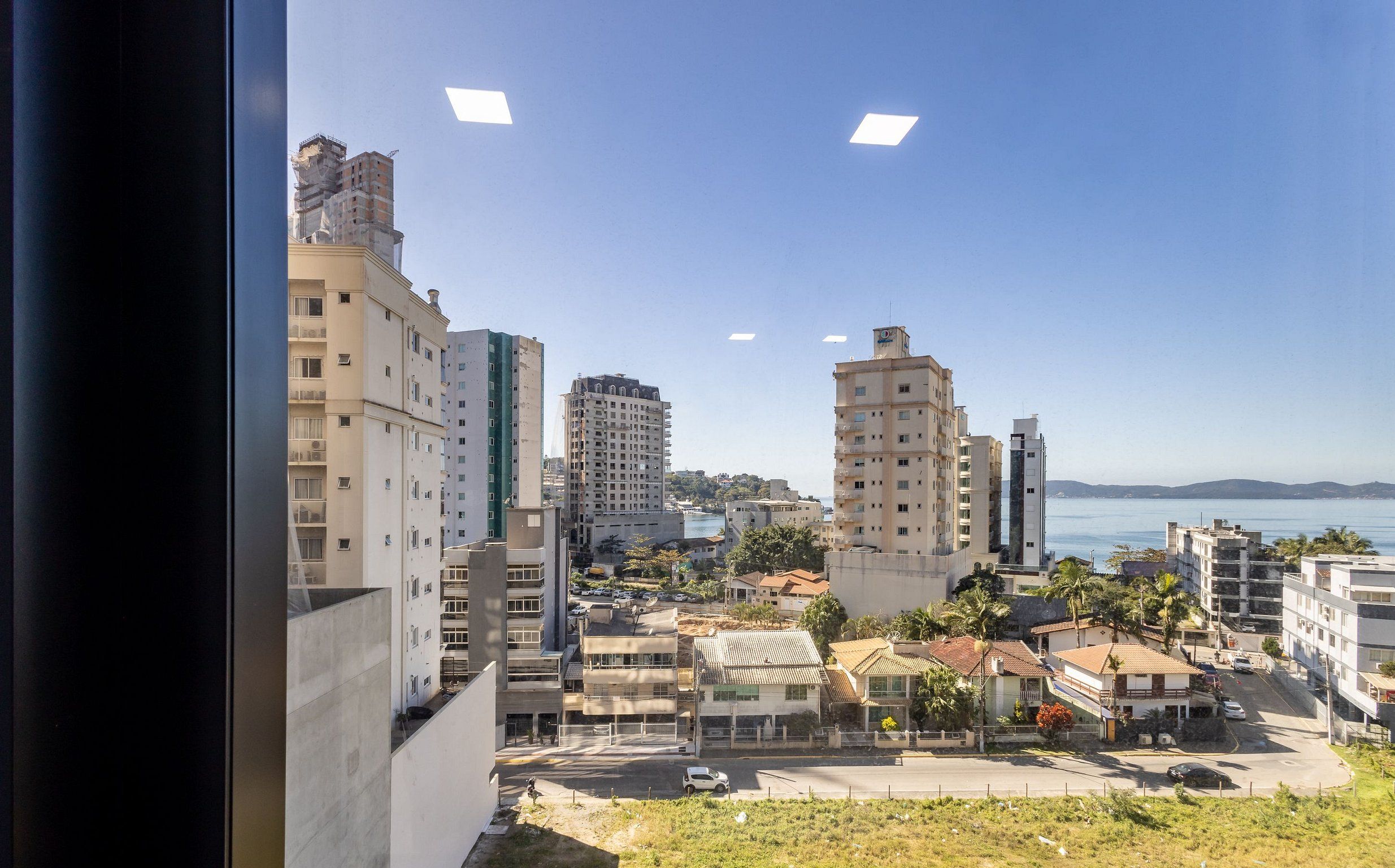 Paisagem costeira urbana com edifícios altos, céu claro e vista para o mar.