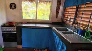 Cozinha compacta com fogão a gás, pia e janela com persianas.
