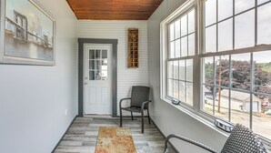 Quarto com teto de madeira, uma janela ampla com vista, uma porta e uma cadeira.