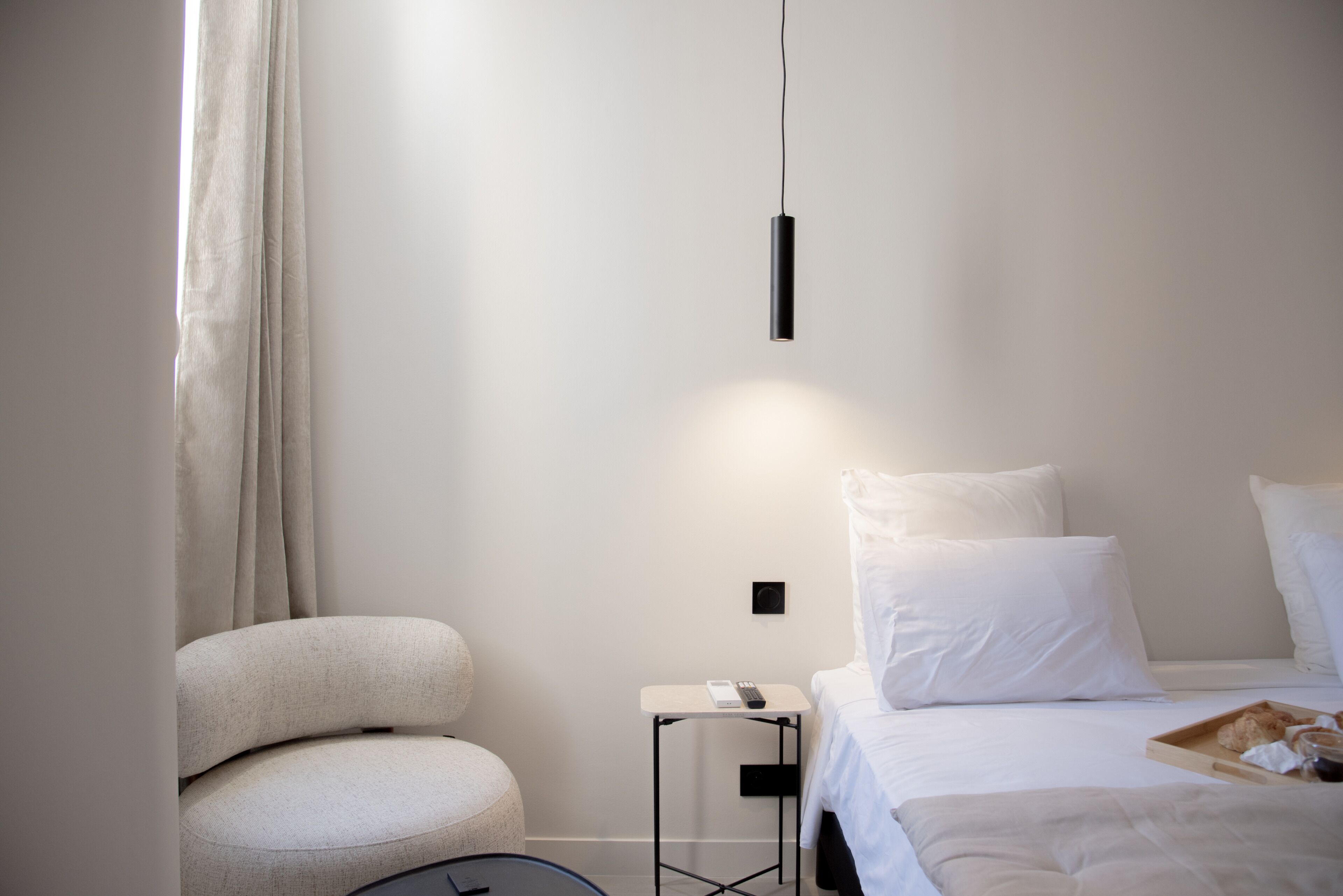 Quarto de hotel moderno com cama, mesa de cabeceira e uma cadeira.