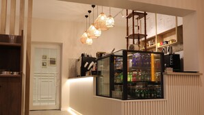 Uma área de bar com balcão, luminárias pendentes e uma vitrine de vidro.