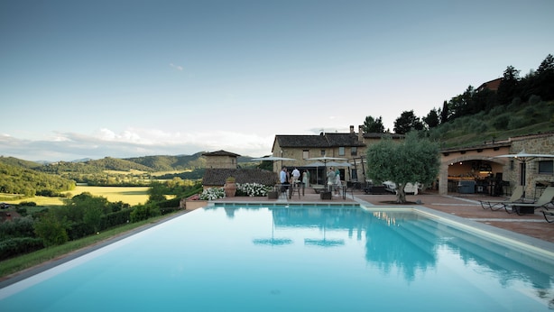 Piscina com vista para uma colina e um edifício com área externa para sentar.