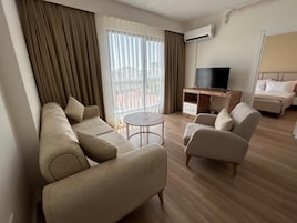 Quarto de hotel moderno com sofá, televisão e cama.