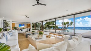 Sala de estar moderna com uma grande janela com vista para uma piscina e o oceano.