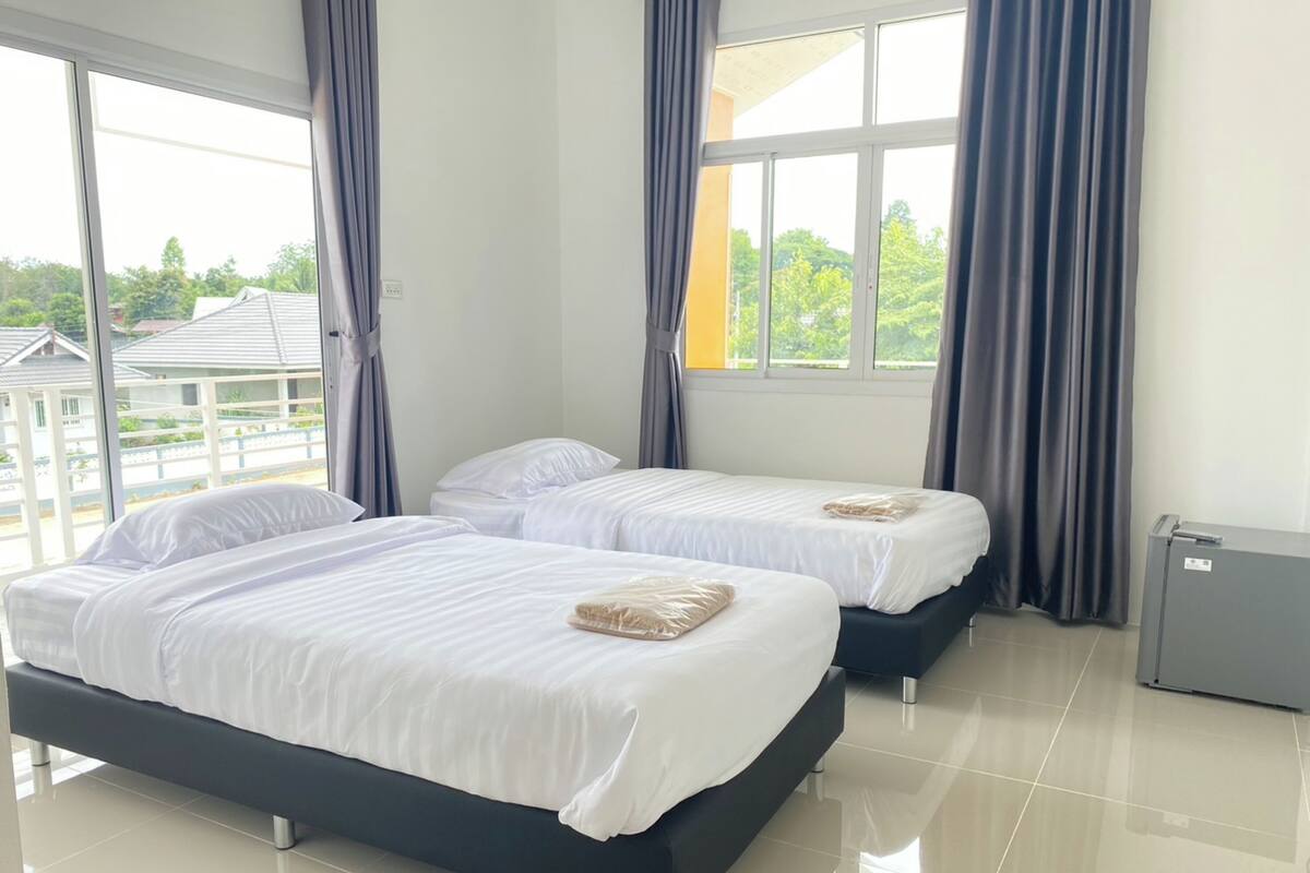 Quarto de hotel com duas camas, janelas amplas e vista para o exterior.