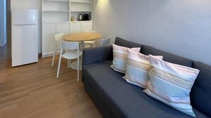 Um espaço compacto com cozinha americana, área de refeições e sofá com almofadas estampadas.